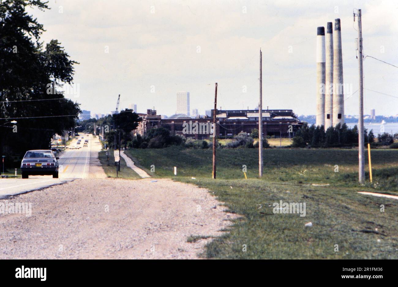 Car driving toward downtown Milwaukee, a factory with smokestacks on ...