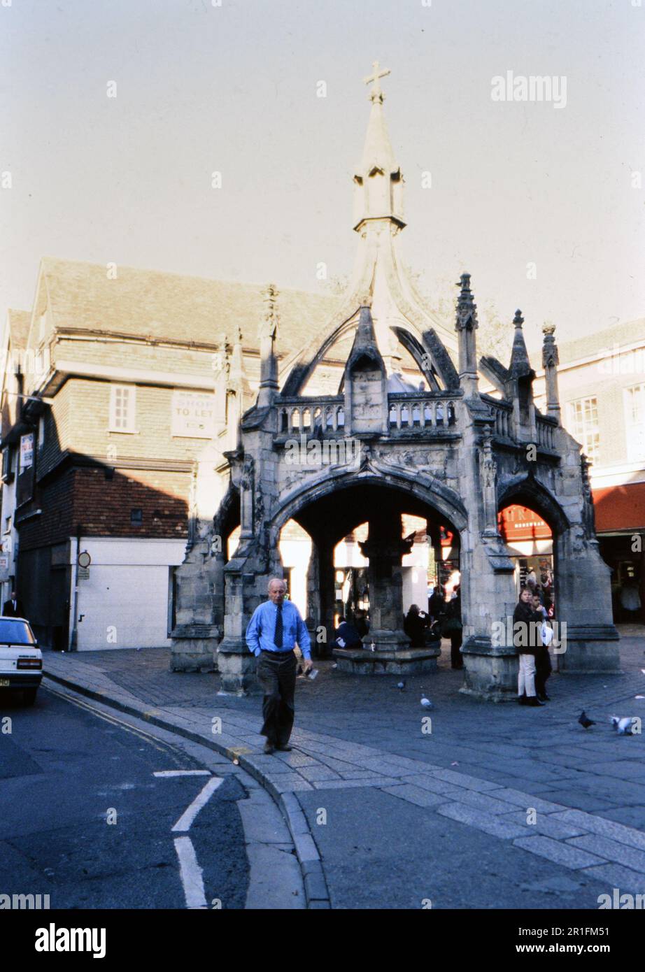 Older gentleman walking on a sidewalk pass the Poultry Cross, a market ...