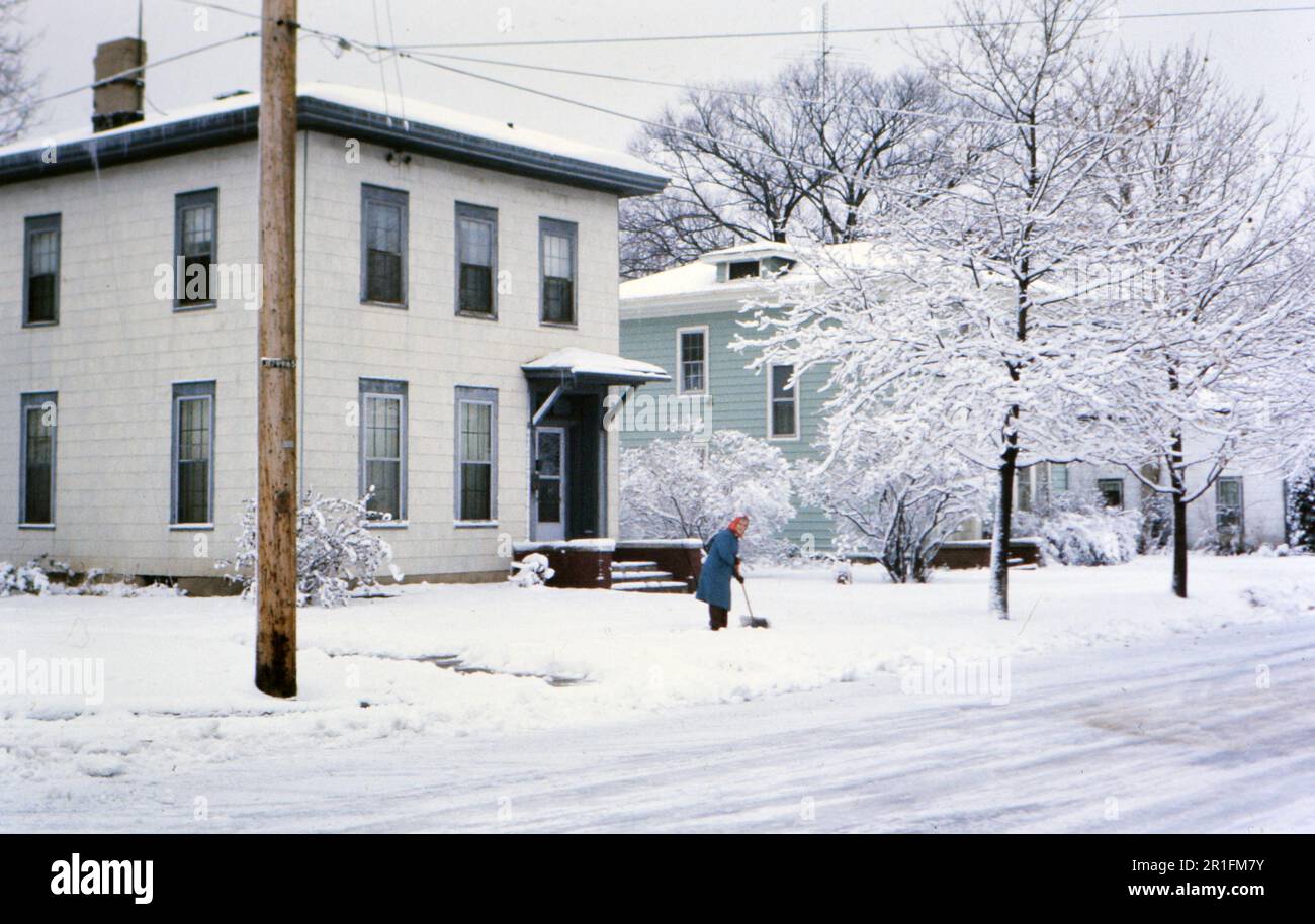 Elderly woman shoveling snow outside her house in winter ca. 1976 Stock Photo - Alamy