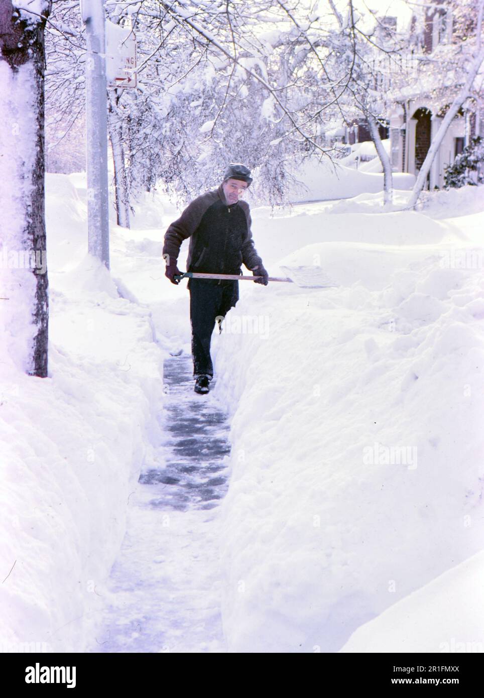 Man shoveling a sidewalk, clearing the sidewalk in front of his ...