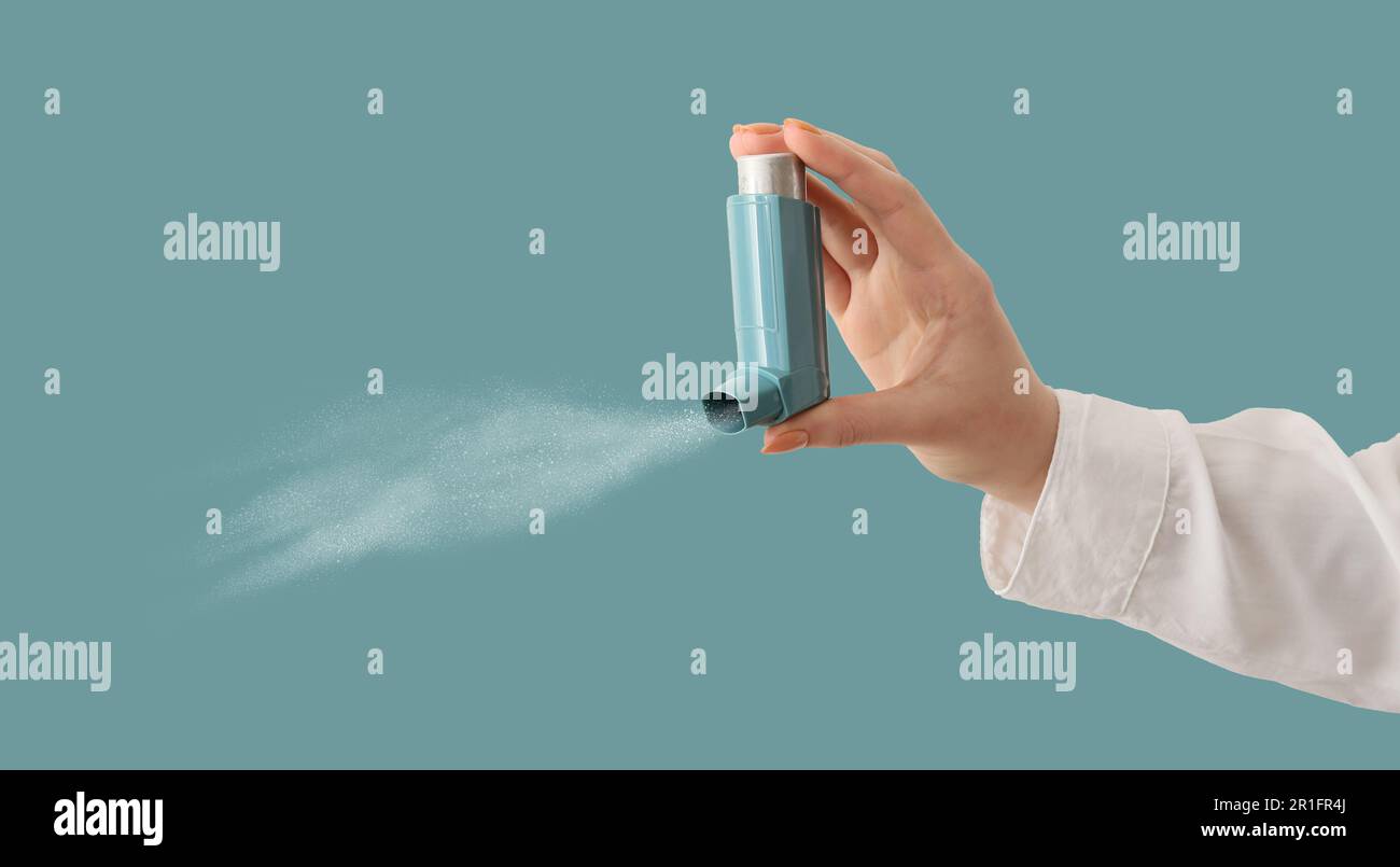 Hand holding inhaler on light blue background Stock Photo - Alamy