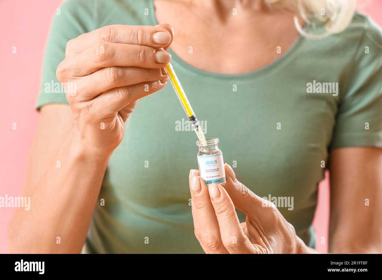 Mature diabetic woman with syringe and insulin on pink background ...