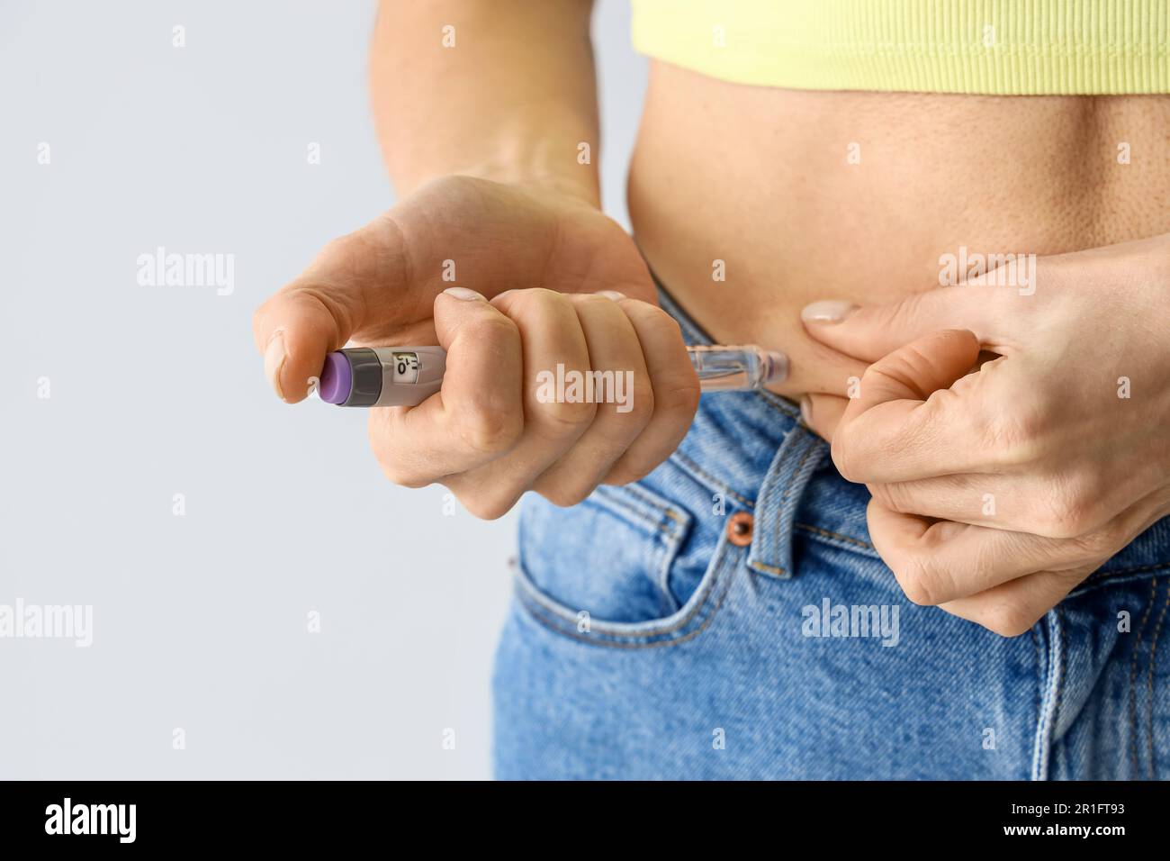 Mature diabetic woman giving herself insulin injection on light ...