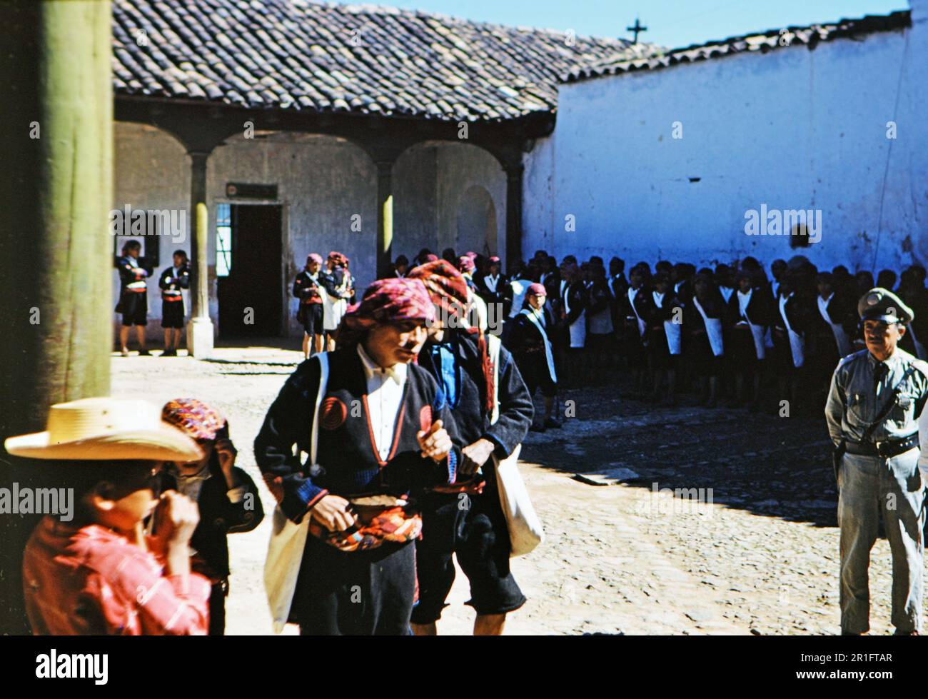 A police officer looks at a man, one of many dressed in a traditional ...