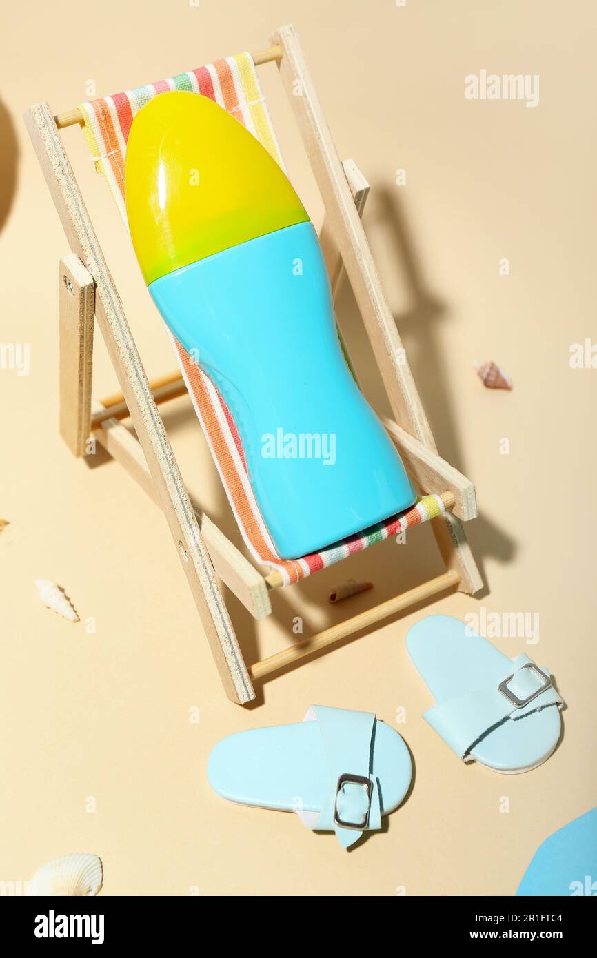 Creative composition with miniature deckchair and sunscreen on beach ...