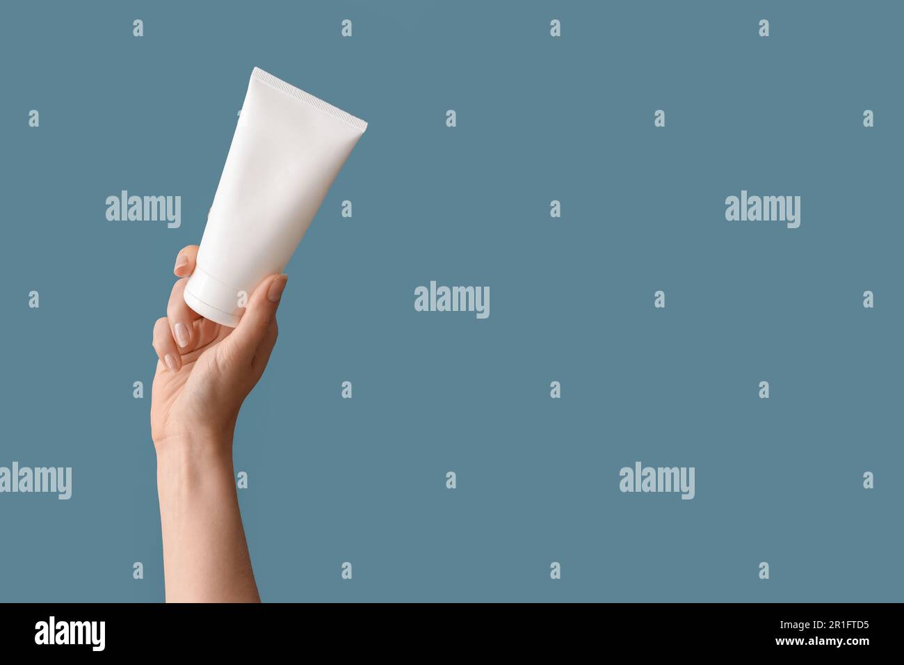 Hand holding tube with cosmetic product on blue background Stock Photo ...