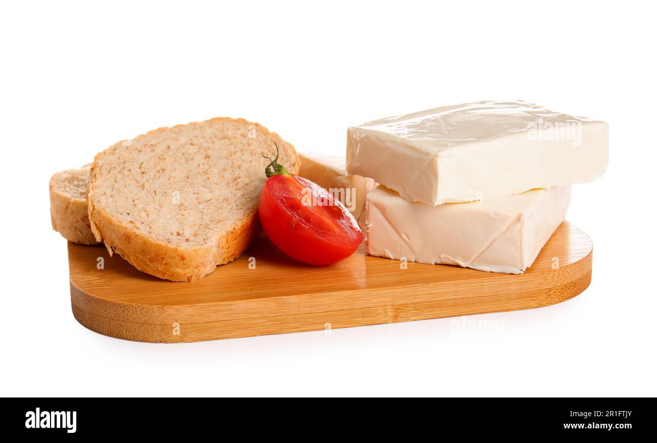Board with processed cheese, bread and tomatoes on white background ...