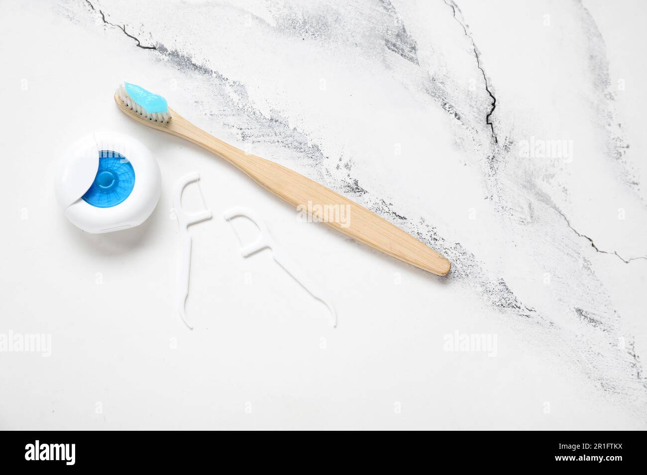 Dental floss, toothpicks and bamboo toothbrush on white marble ...
