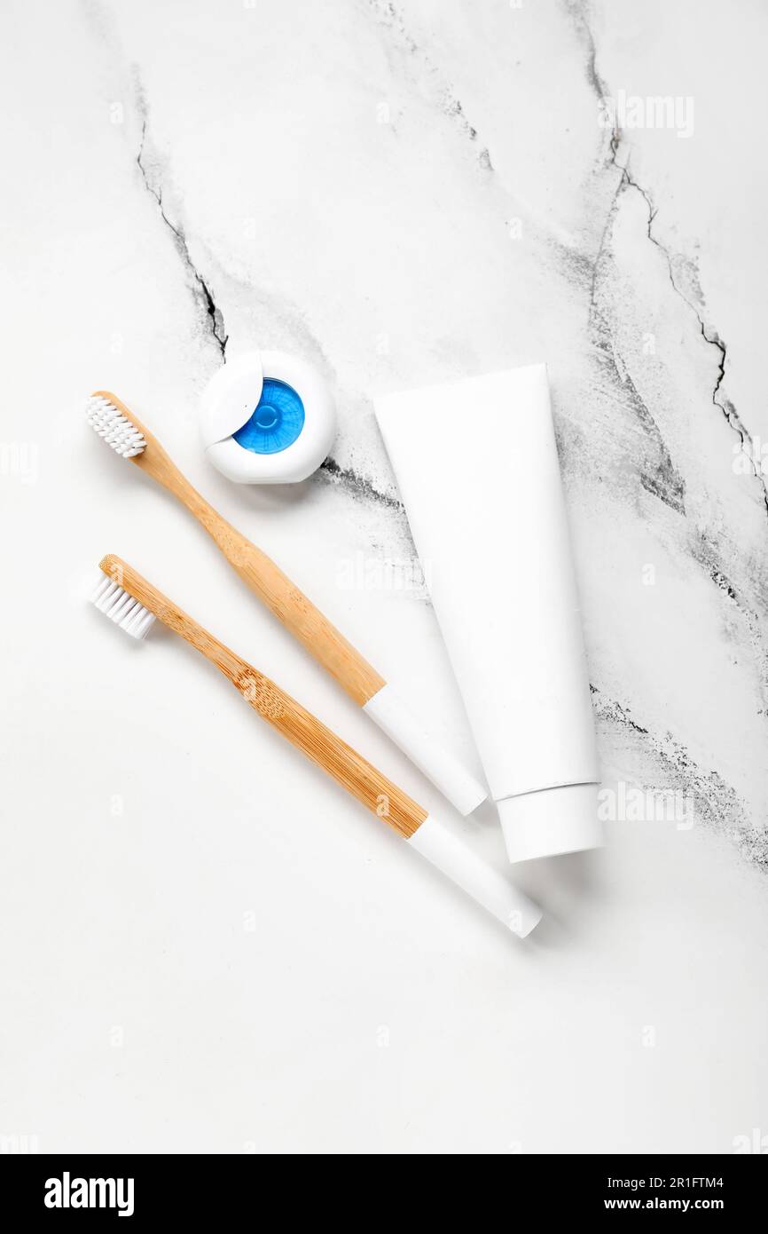 Dental floss, paste and bamboo toothbrush on white marble background ...
