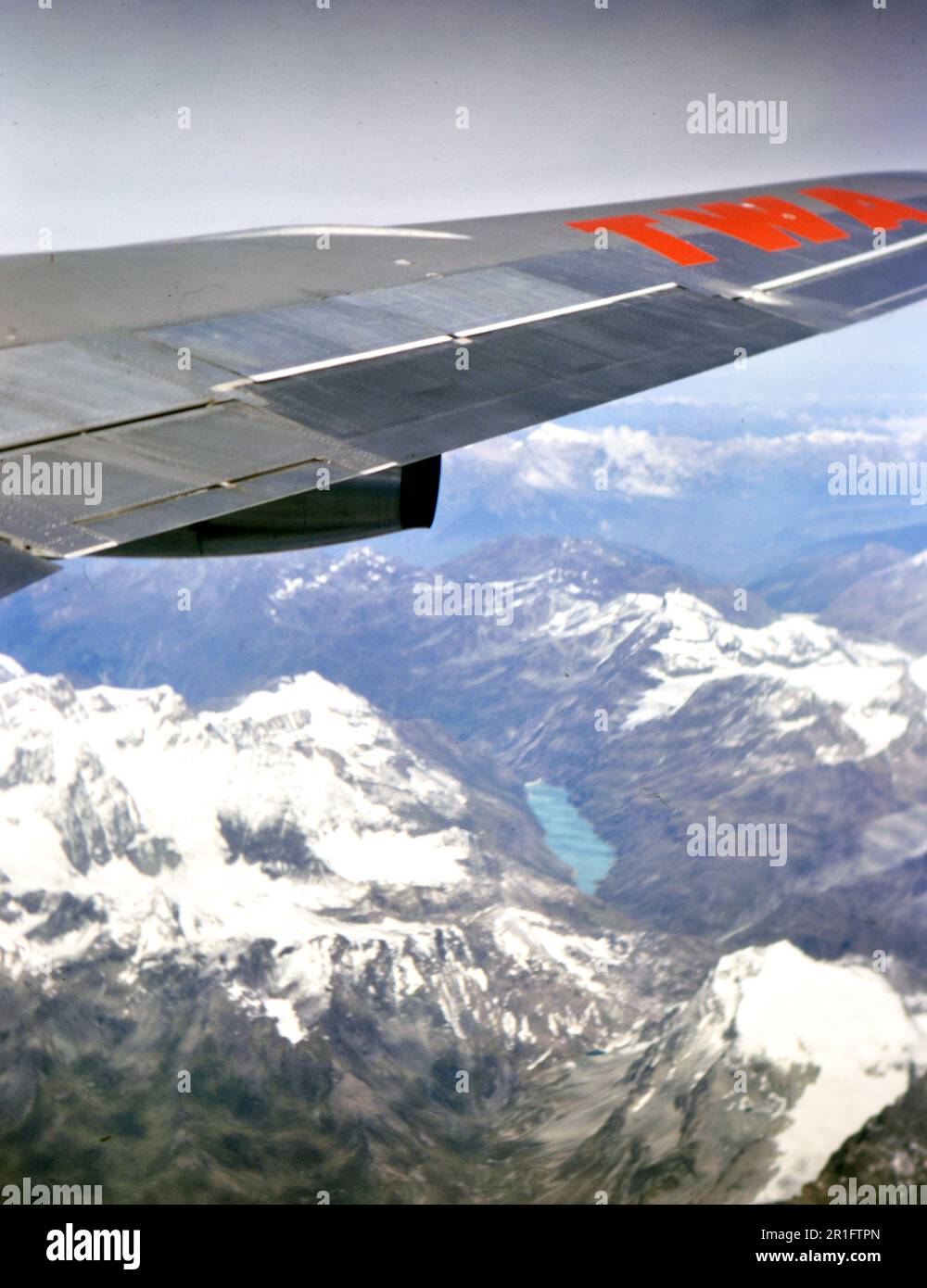 View of a wing of a TWA plane as it flies over the Alps ca. 1968 Stock ...