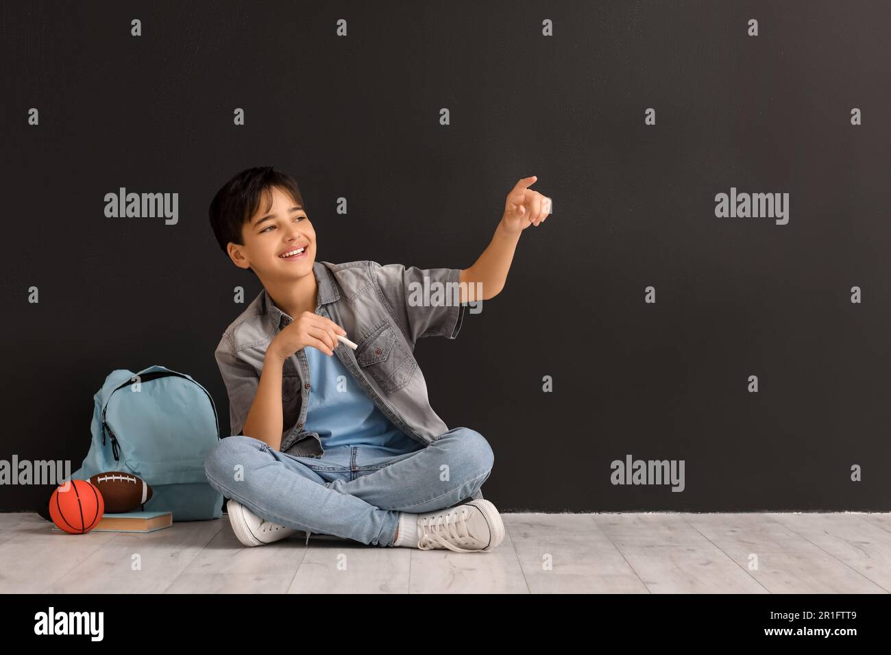 Little boy pointing at something near blackboard. Children's Day ...