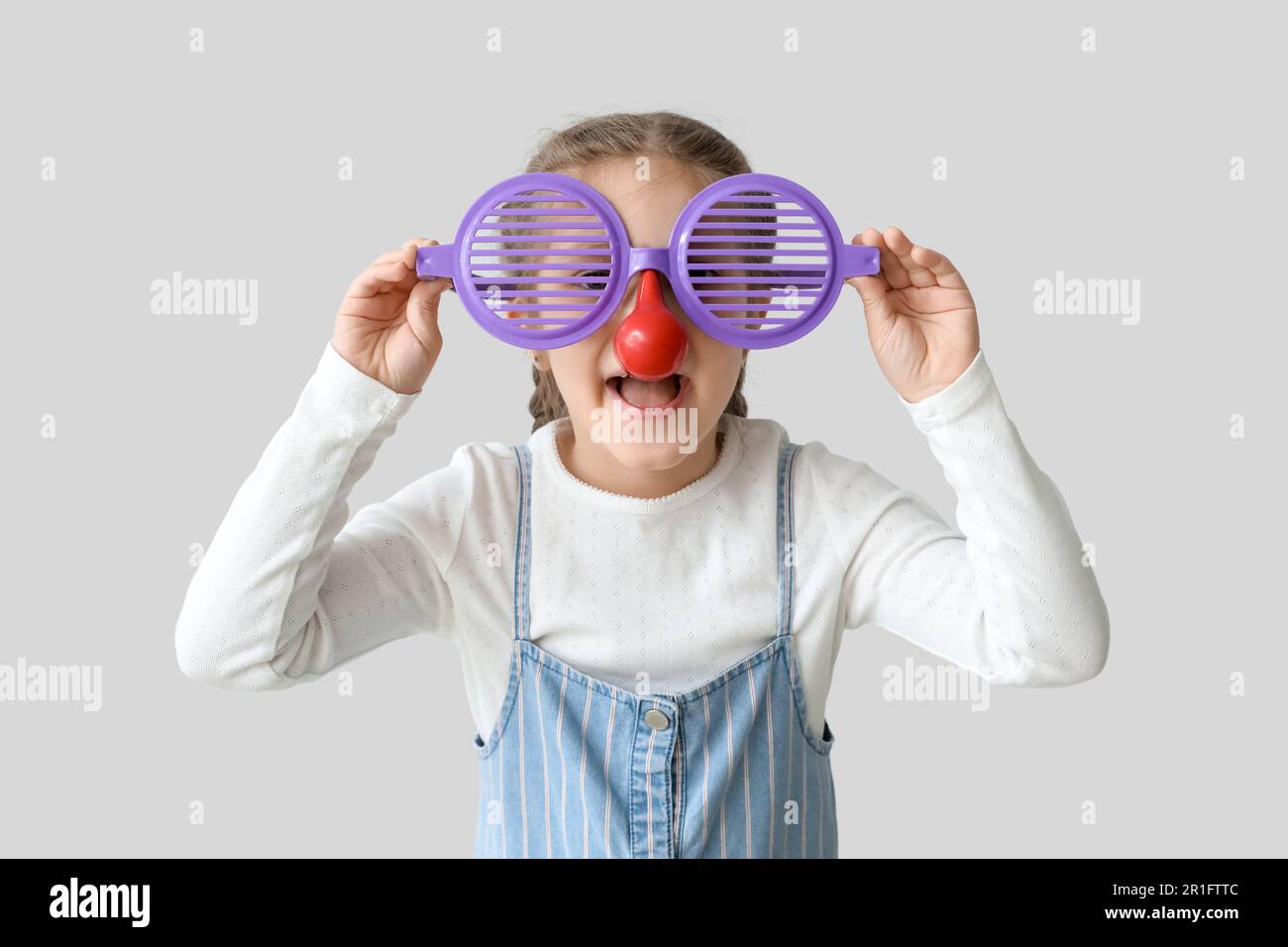 Little girl in funny disguise on light background. Children's Day ...