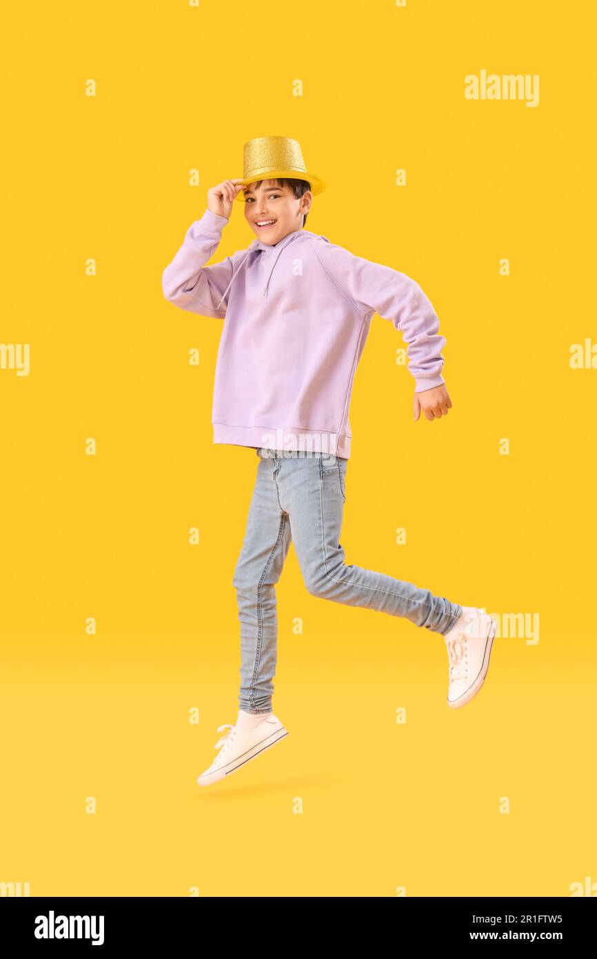 Little boy in party hat jumping on yellow background. Children's Day ...