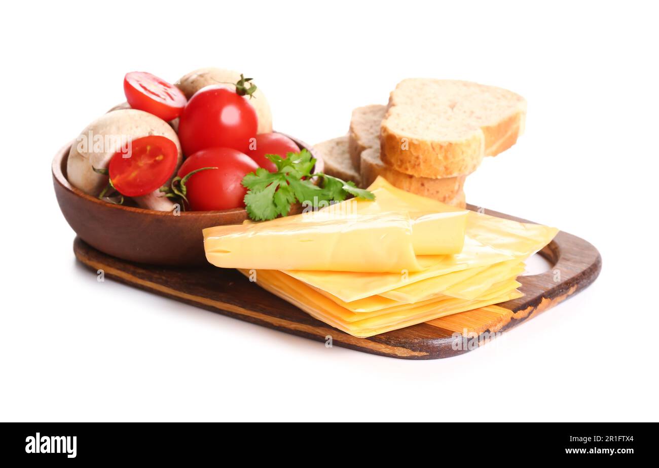 Board of tasty processed cheese with vegetables and bread on white ...