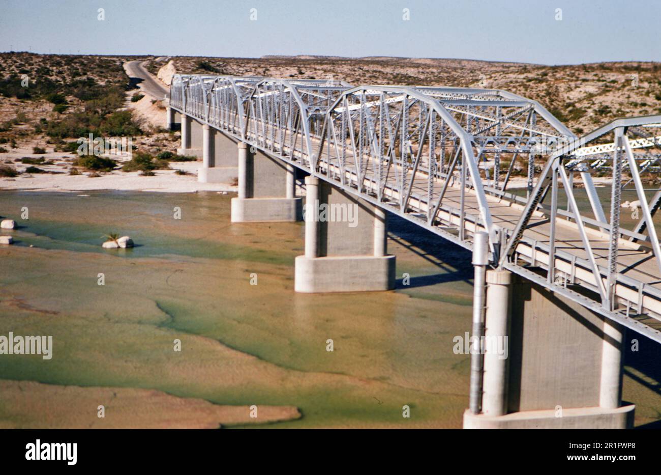 Long steel bridge over a river in a desolate area of Texas ca. 1950 ...