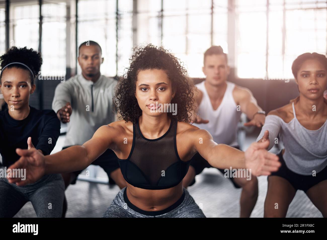 And squat...and hold...a group of young people doing squats together ...