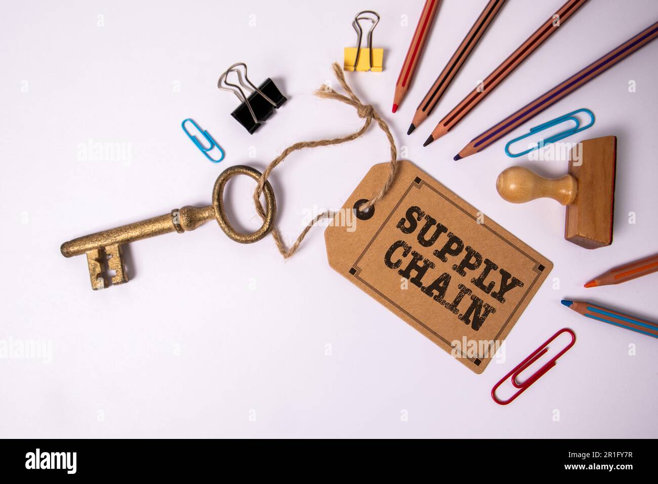 Supply Chain. Key with cardboard price tag and office supplies on white ...