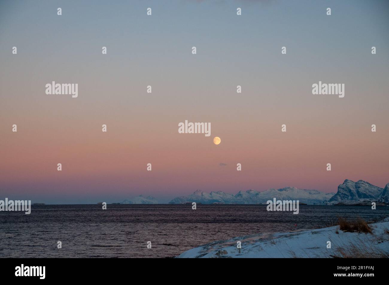 Landscape shot highlighting a near full moon over the rugged mountains ...