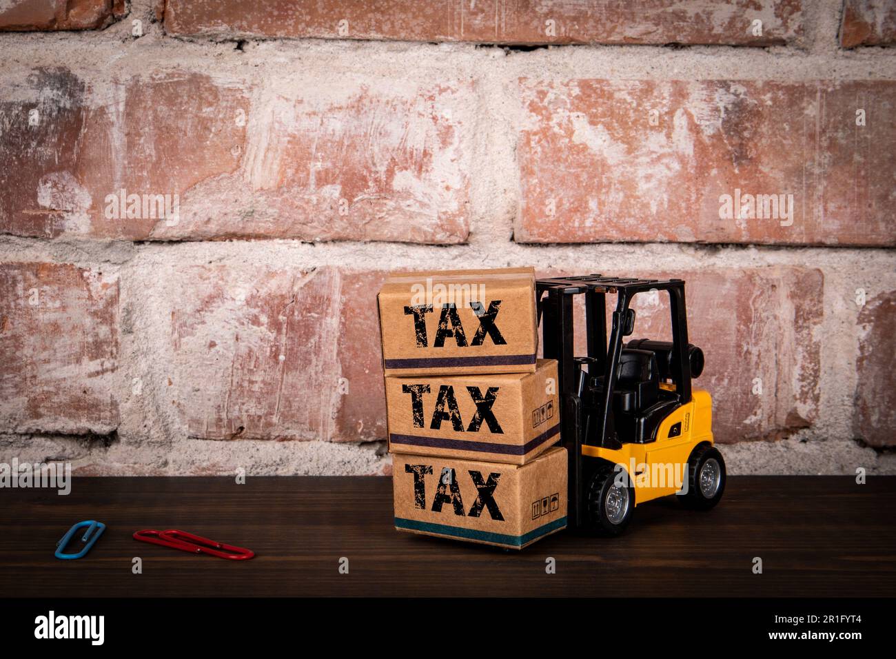 TAX CONCEPT. Miniature cardboard boxes and a forklift on a wooden ...