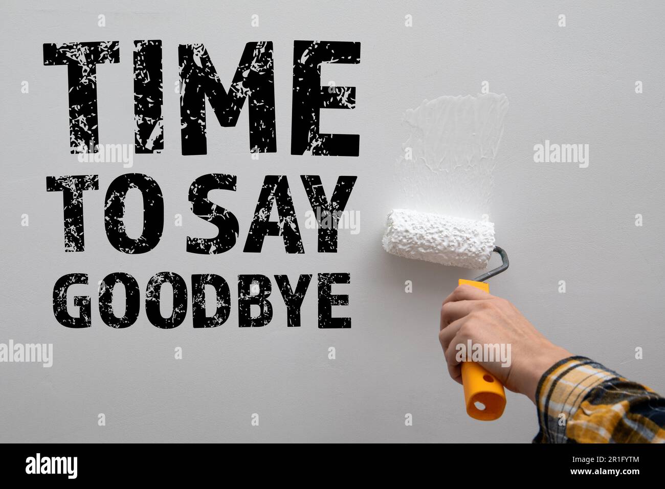 Time To Say Goodbye. Painting a white wall with a paint roller in hand ...