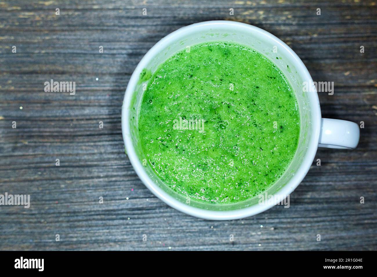Top view to white round wide cup with fresh green soup. Aged wooden ...