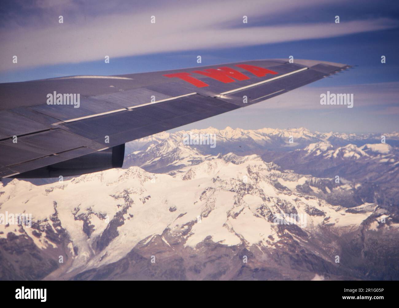 View of a wing of a TWA plane as it flies over the Alps ca. 1968 Stock ...