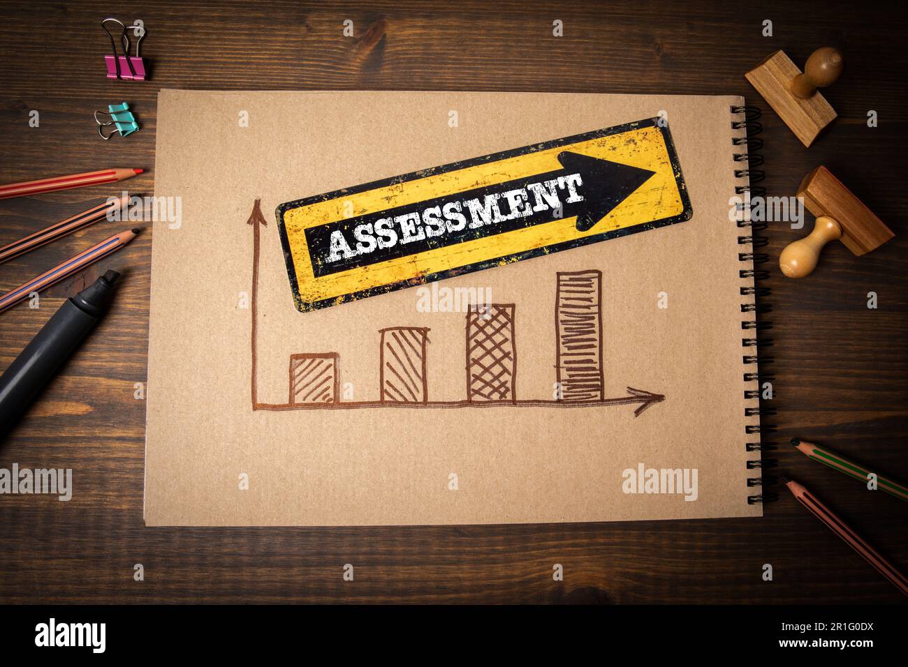 Assessment Concept. A table with a pointing arrow in the notepad. wood ...