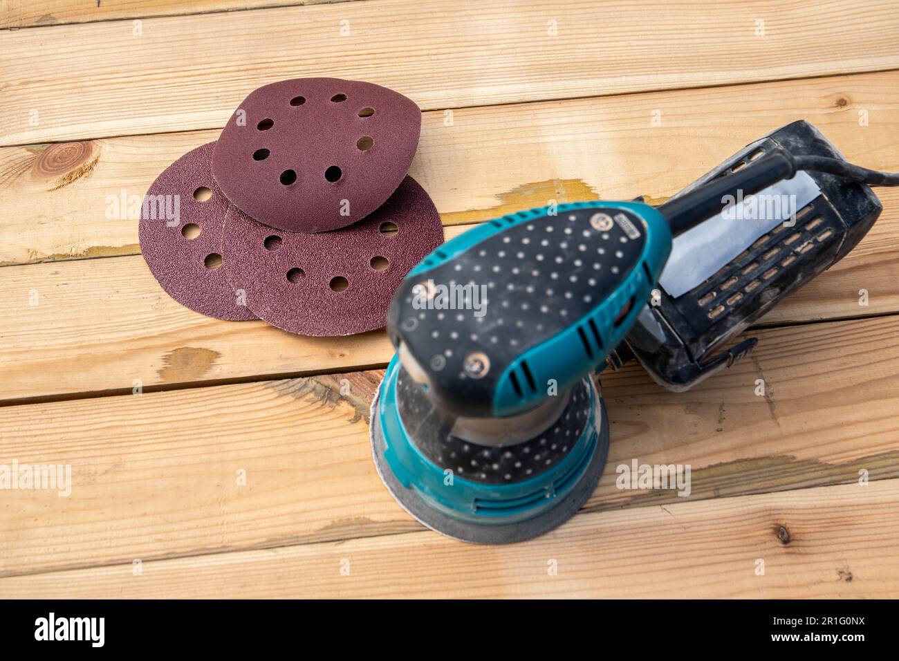 Round sandpaper discs and orbital sander. Wooden background Stock Photo ...