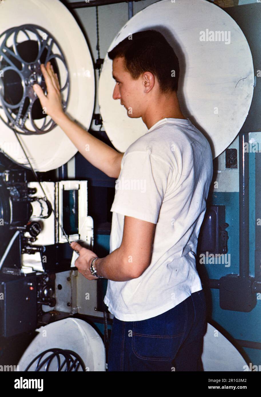 A projectionist loading film into a film projector at a movie theater ...