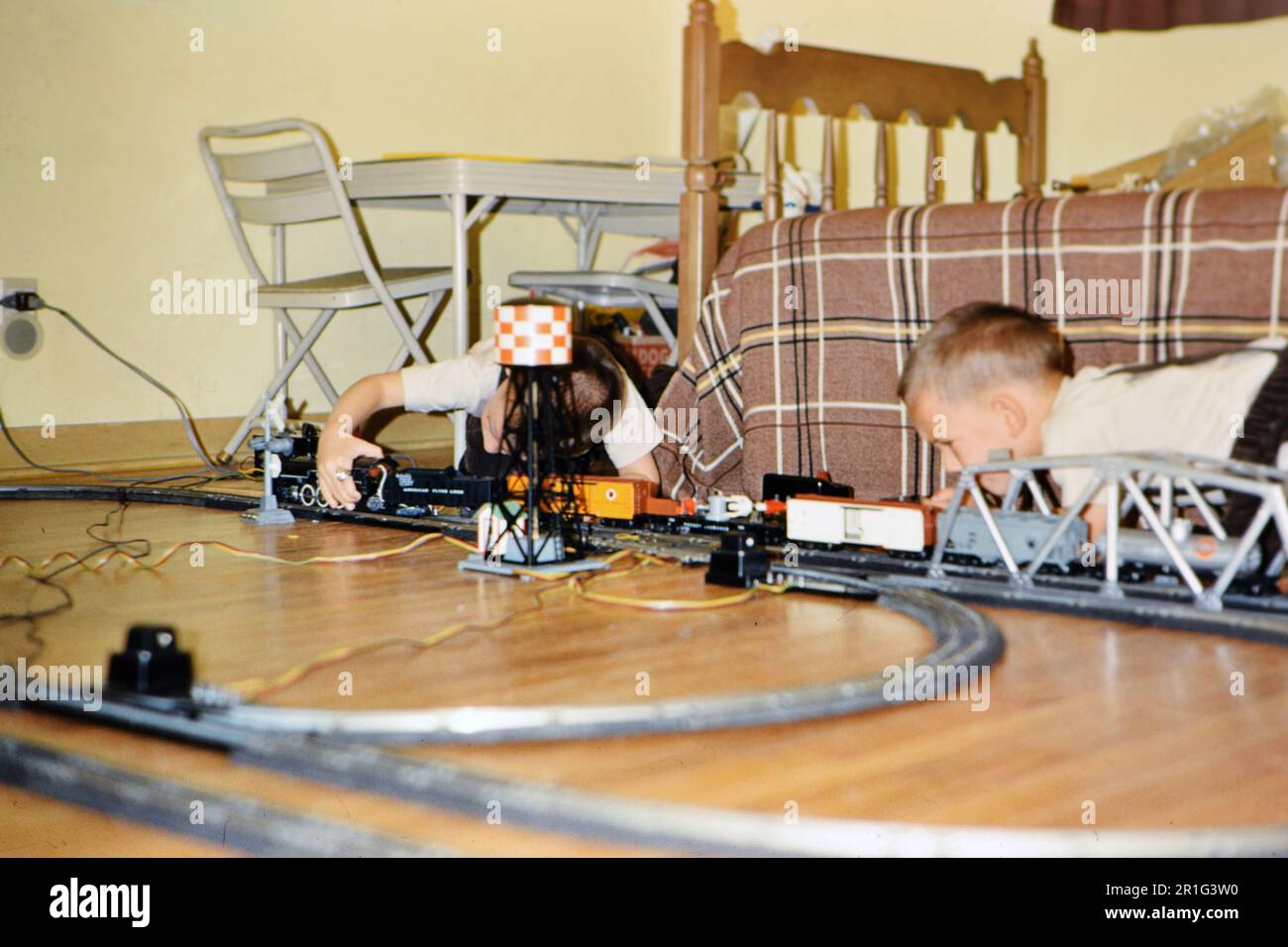 Two children playing with a toy train set in their bedroom ca. 1960 ...