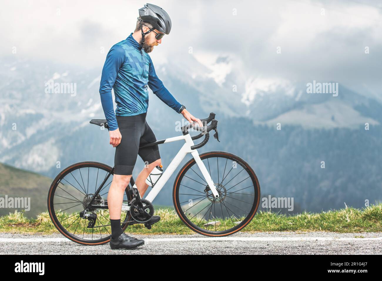 A male cyclist standing on his bicycle on a mountain road Stock Photo ...