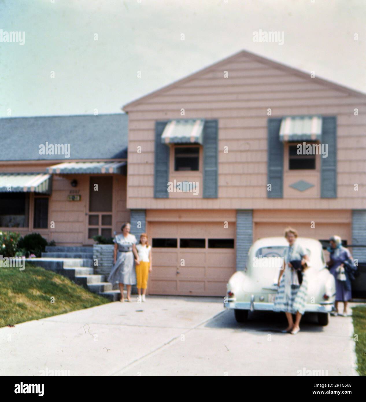 Various family members pose for a photo outside a pink suburban home ca ...