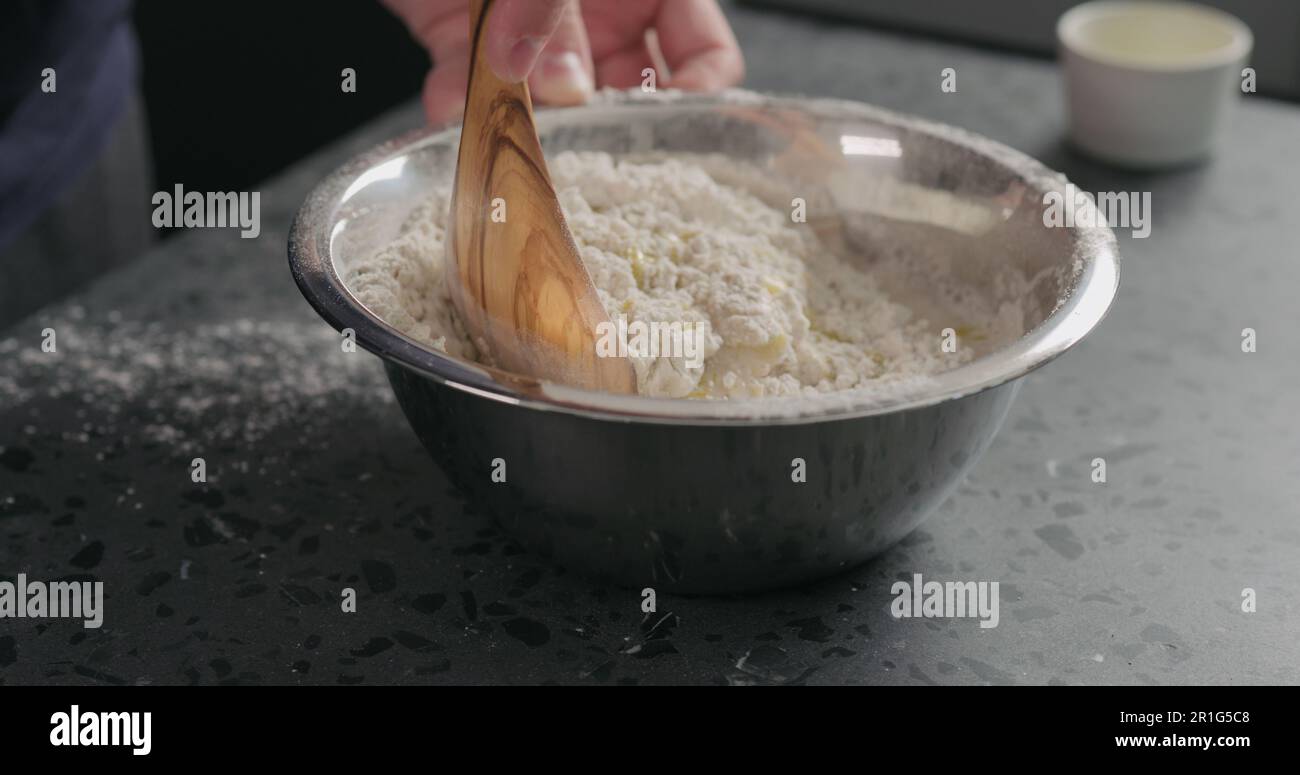 Mixing the water and oil into flour to make bread hi-res stock ...