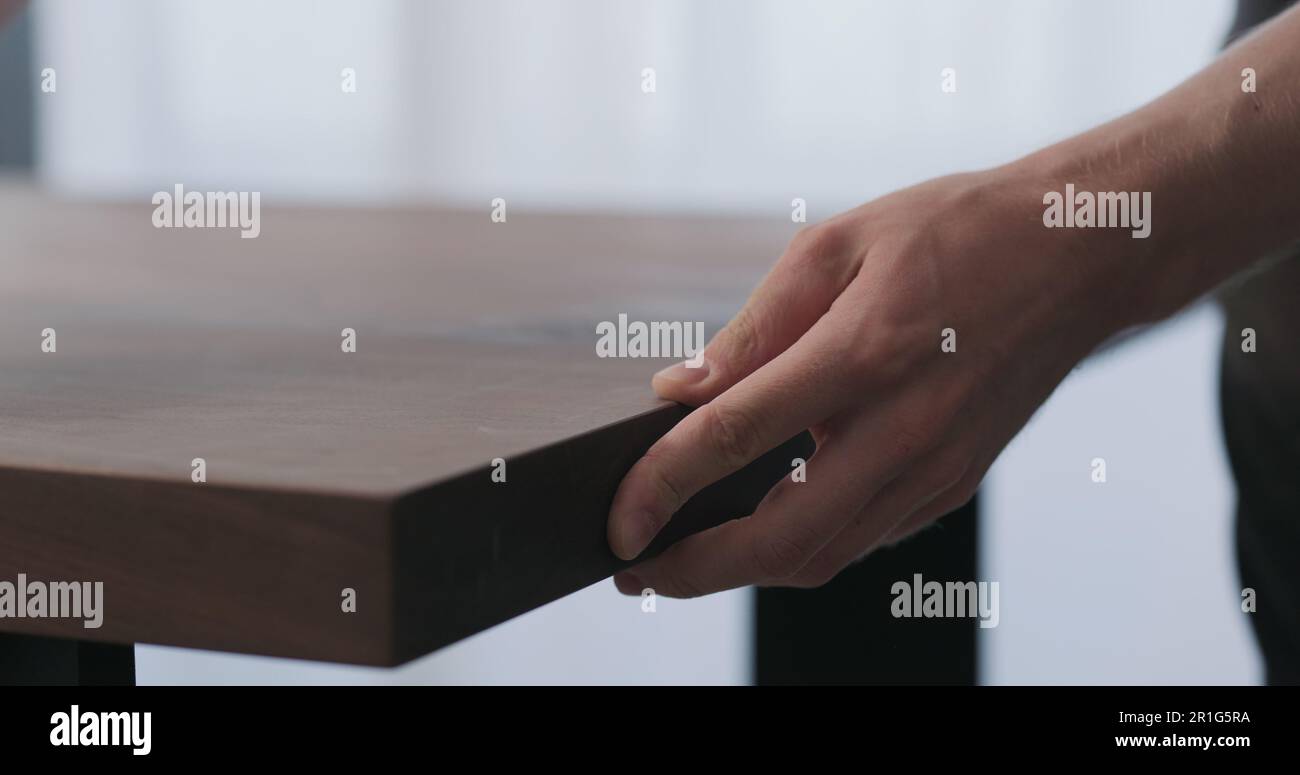 man hand sanding toned walnut table surface before applying finish ...
