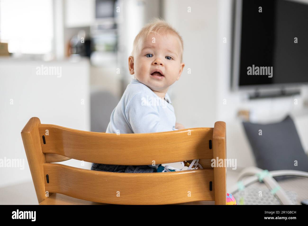 Happy infant sitting in traditional scandinavian designer wooden high ...