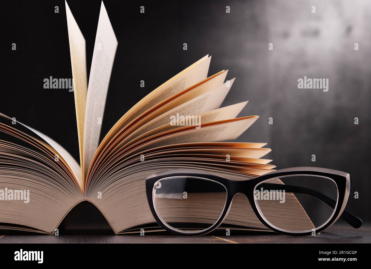 Composition with open book and glasses on the table Stock Photo - Alamy