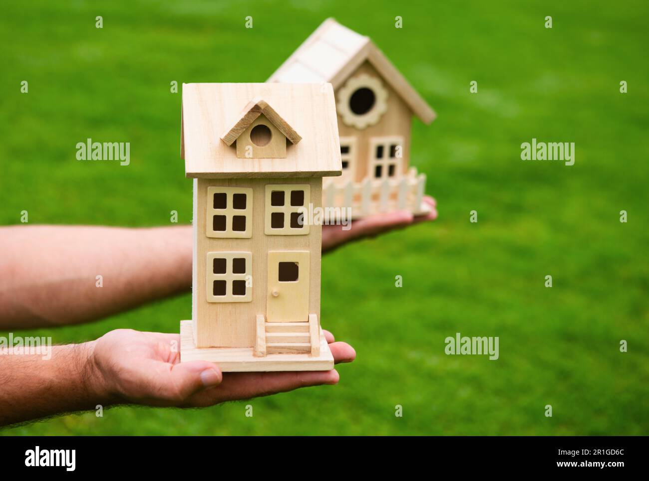 Neighbors house concept. House in hand against spring green background ...