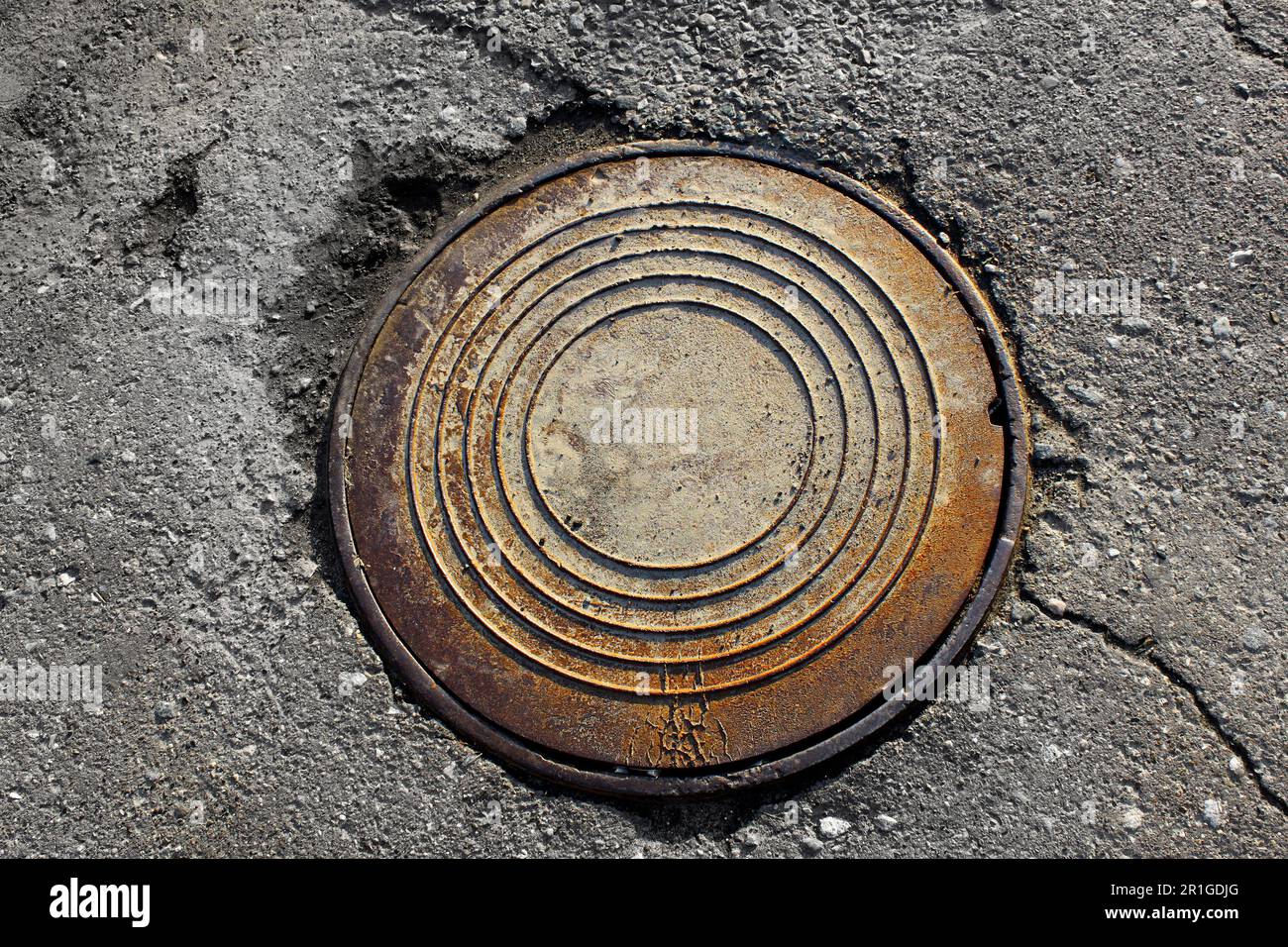 rusty round manhole on the broken asphalt Stock Photo - Alamy