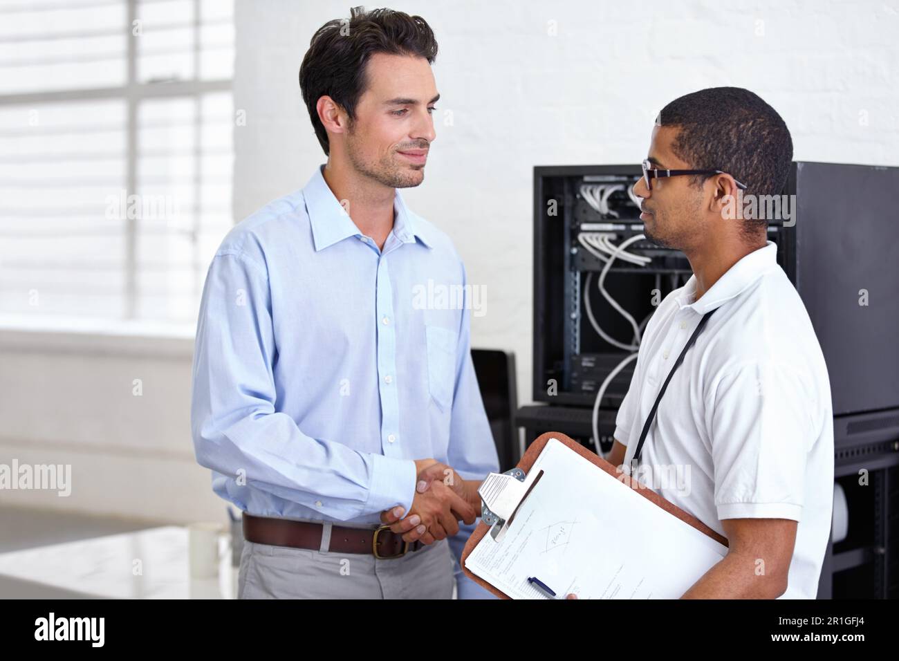 Server room, it support and clipboard with a technician shaking hands ...