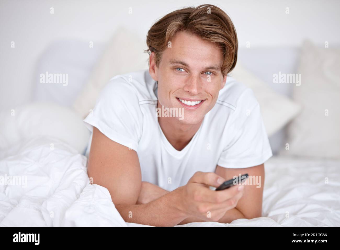 Man, portrait and watching tv on a bedroom bed with happiness and ...