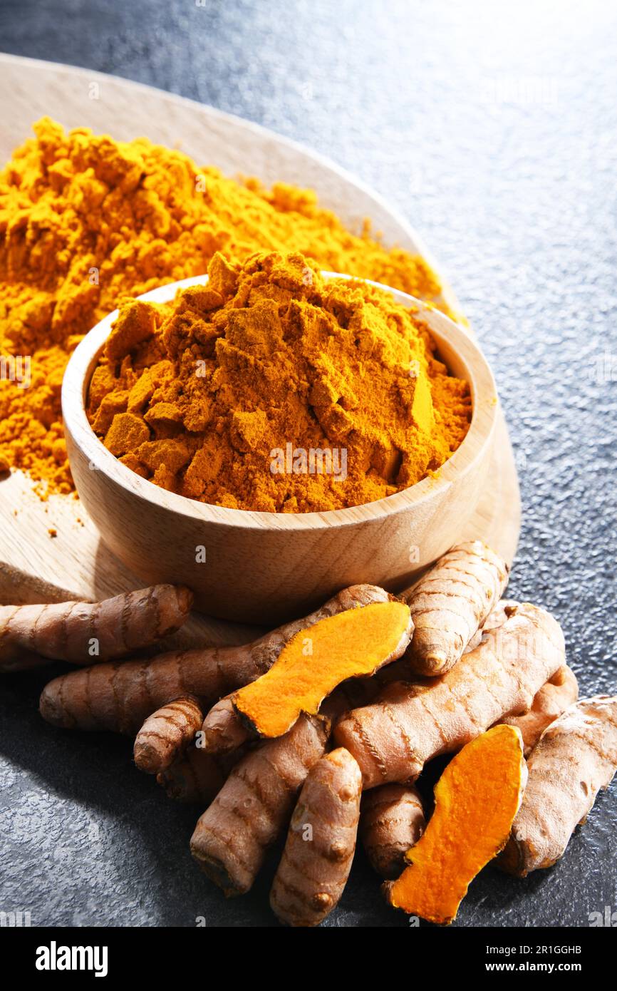 Composition with a bowl of ground turmeric and its fresh rhizome Stock ...