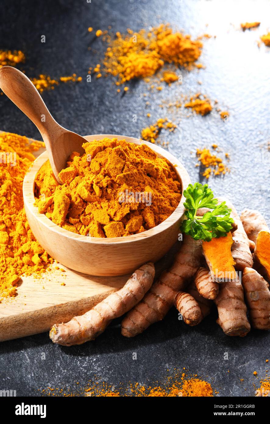 Composition with a bowl of ground turmeric and its fresh rhizome Stock ...