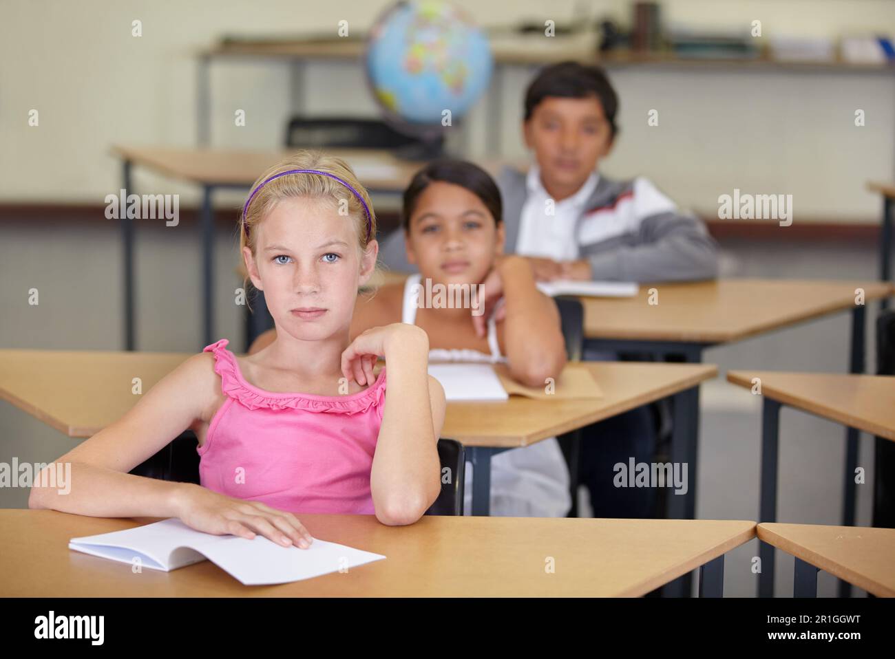Portrait, serious kids and student in classroom with book, ready to ...