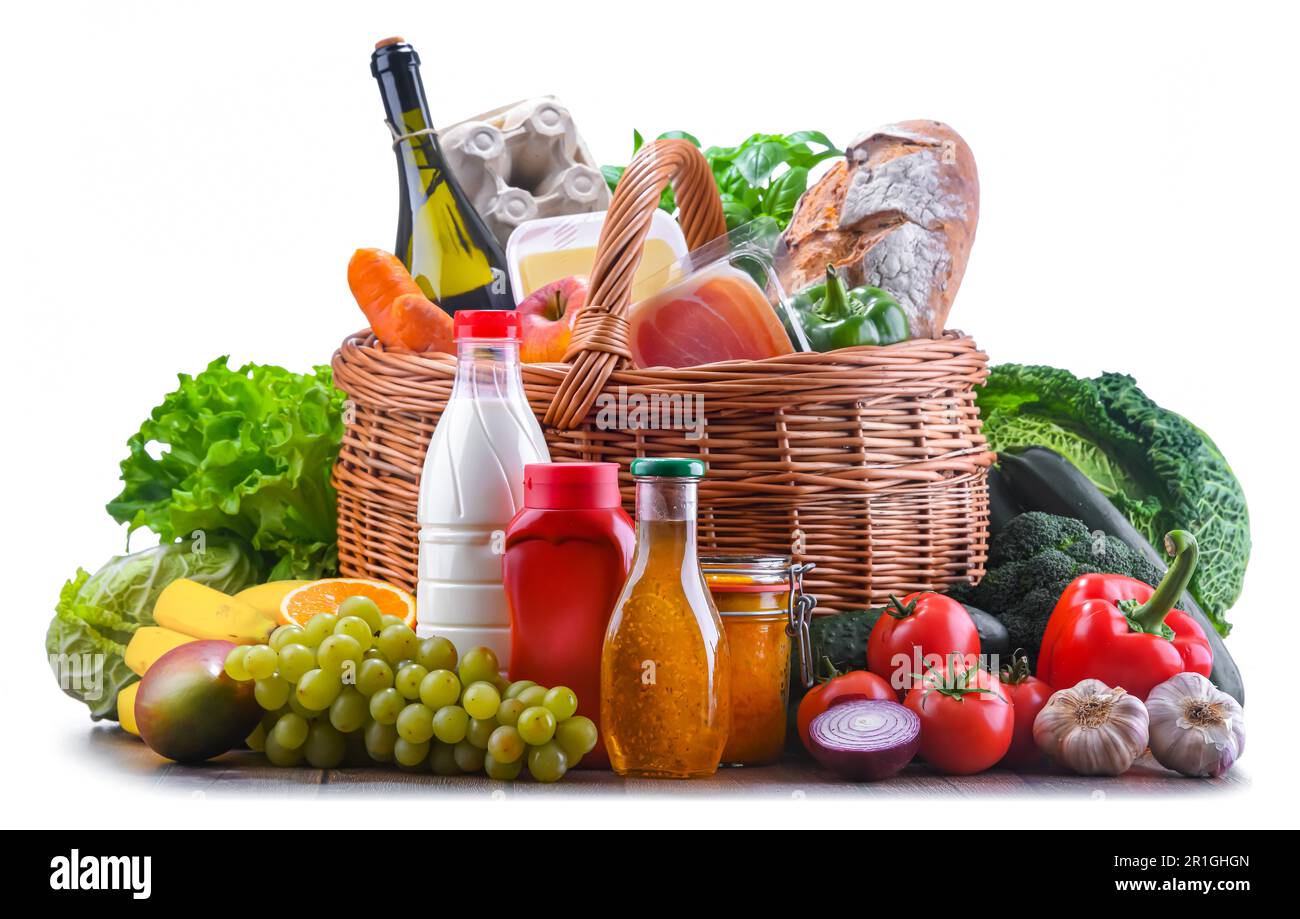 Wicker basket with assorted grocery products including fresh vegetables ...