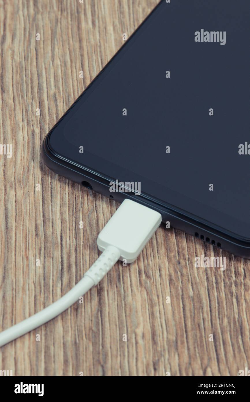 Black smartphone and connected cable of charger. Mobile phone charging ...