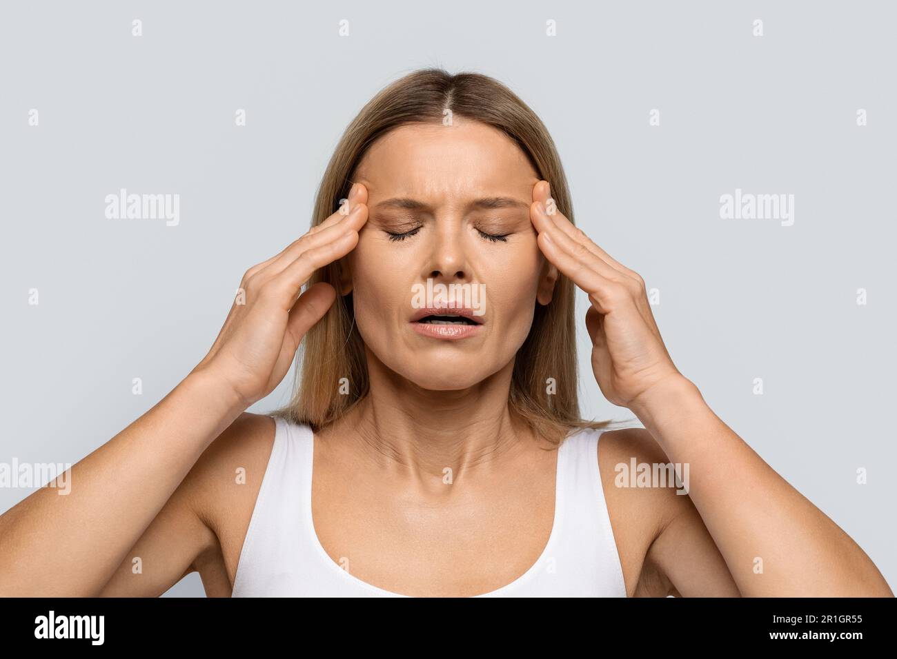 Blonde woman with closed eyes rubbing temples Stock Photo - Alamy