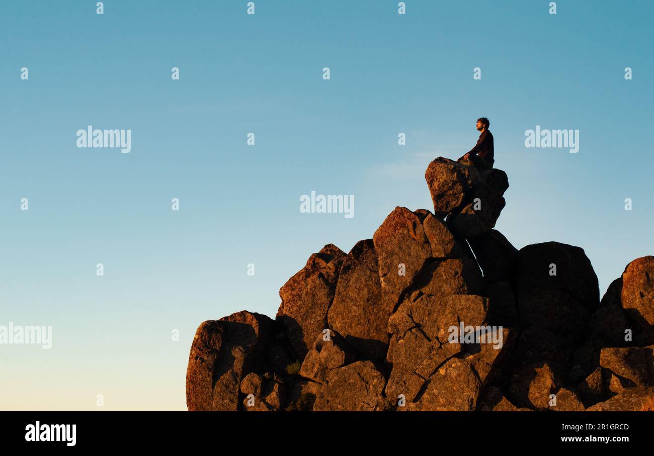 Man Sitting On Top Of Rock Cliff Meditating, Side View Stock Photo - Alamy