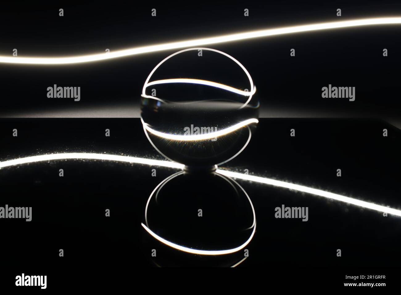 A glowing metallic sphere illuminated in the dark, with its reflection ...