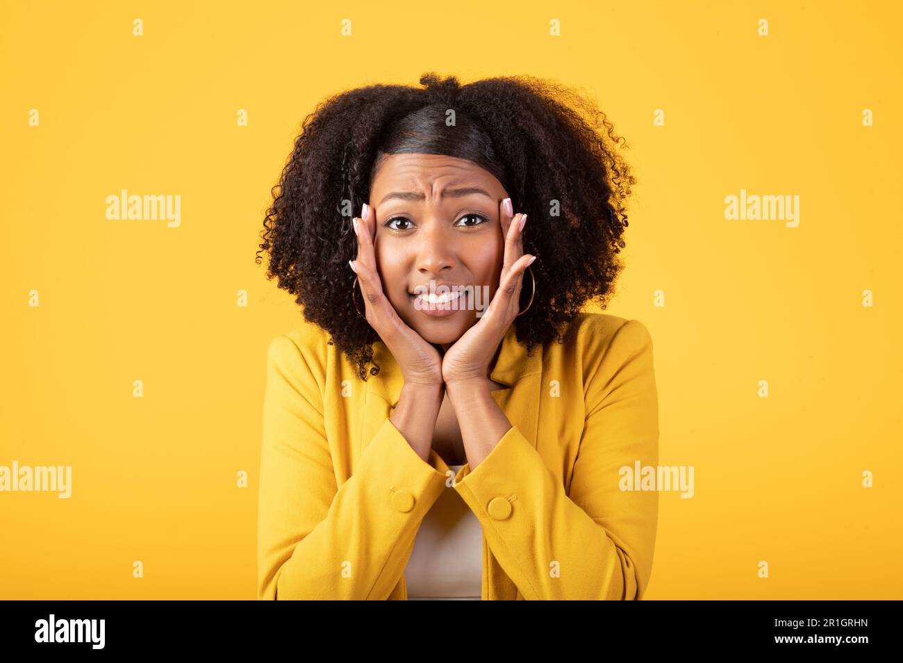 Oh no. Portrait of black lady looking at camera and touching cheeks ...