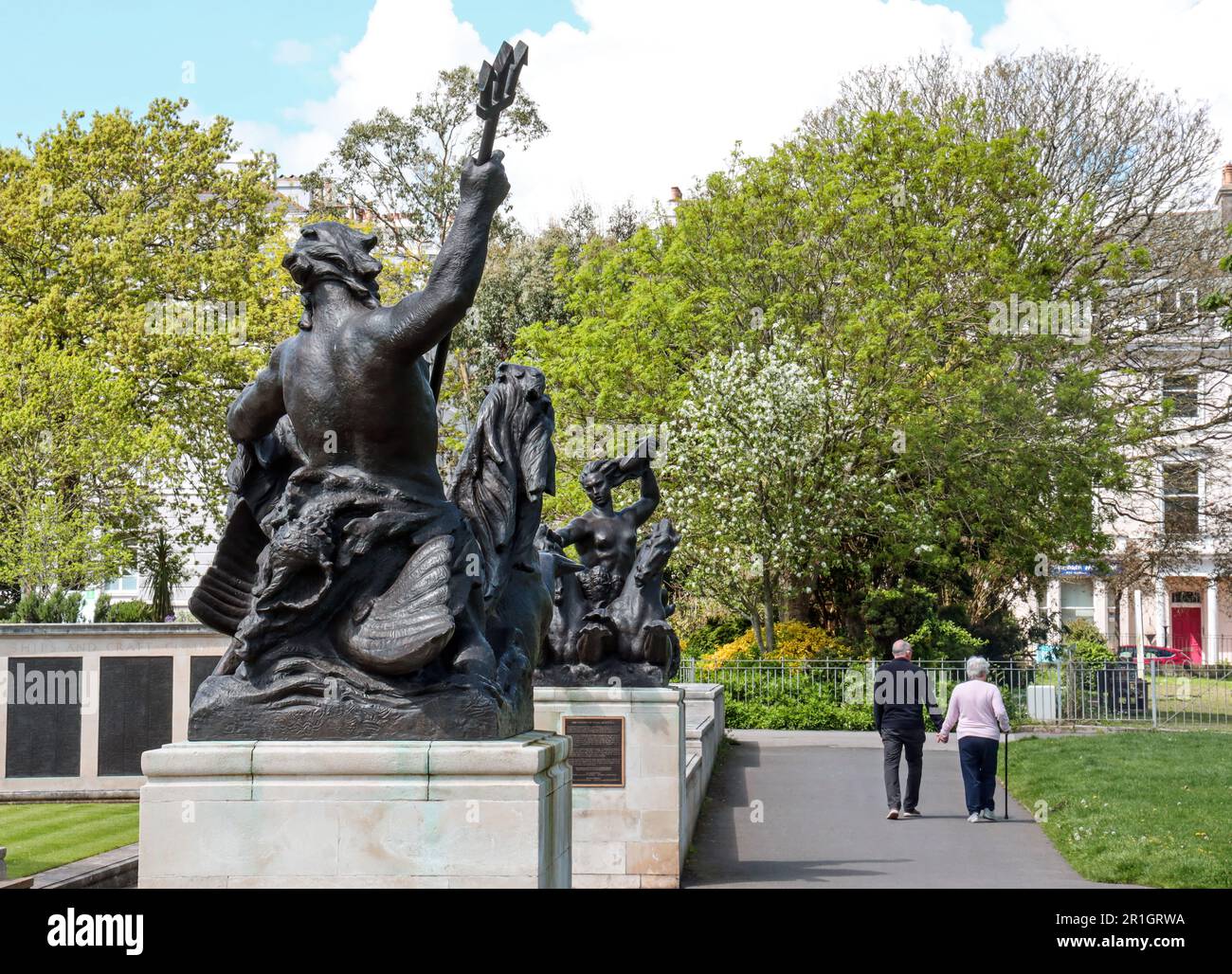 An elderly couple enjoy spring sunshine walking past the bronze statues ...